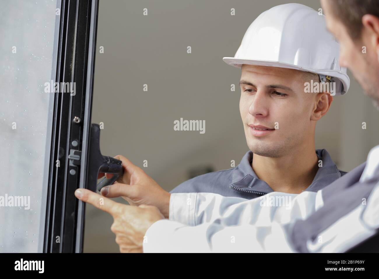 young male worker being shown the latch mechanism on window Stock Photo ...