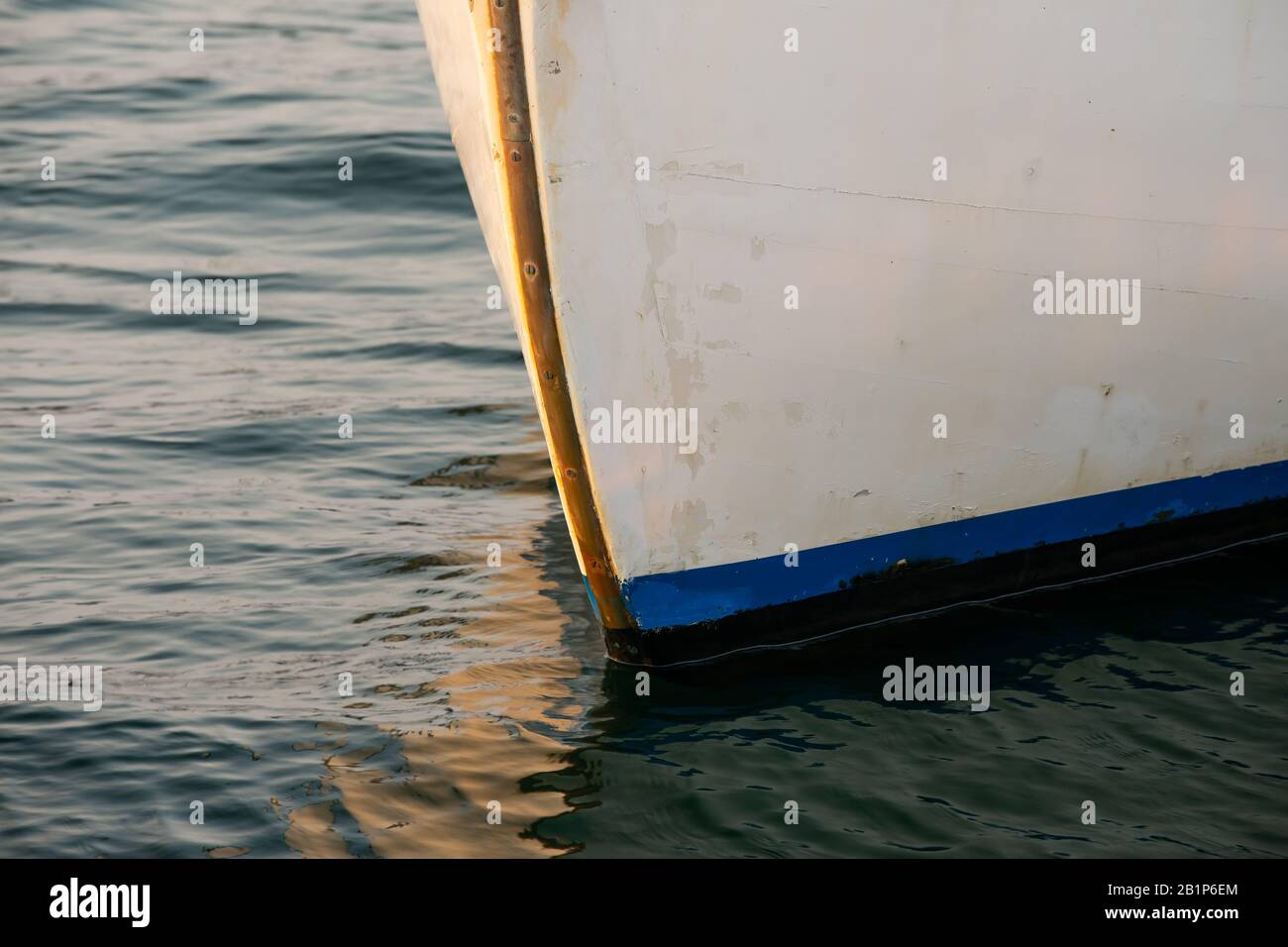 Old white and blue boat hull in the green water at sunset Stock Photo ...