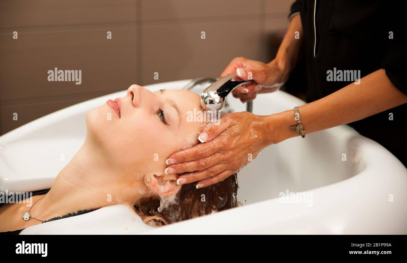 Hair stylist at work - hairdresser washing hair to the customer before ...