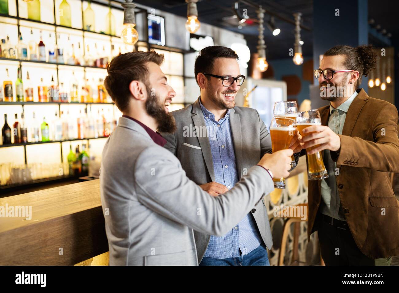Happy young business men talking and drinking beer in a pub Stock Photo ...