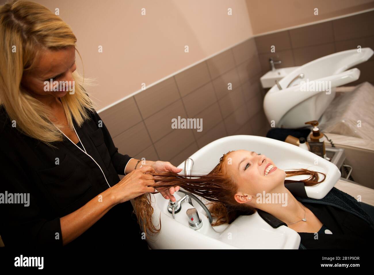 Hair stylist at work - hairdresser washing hair to the customer before ...