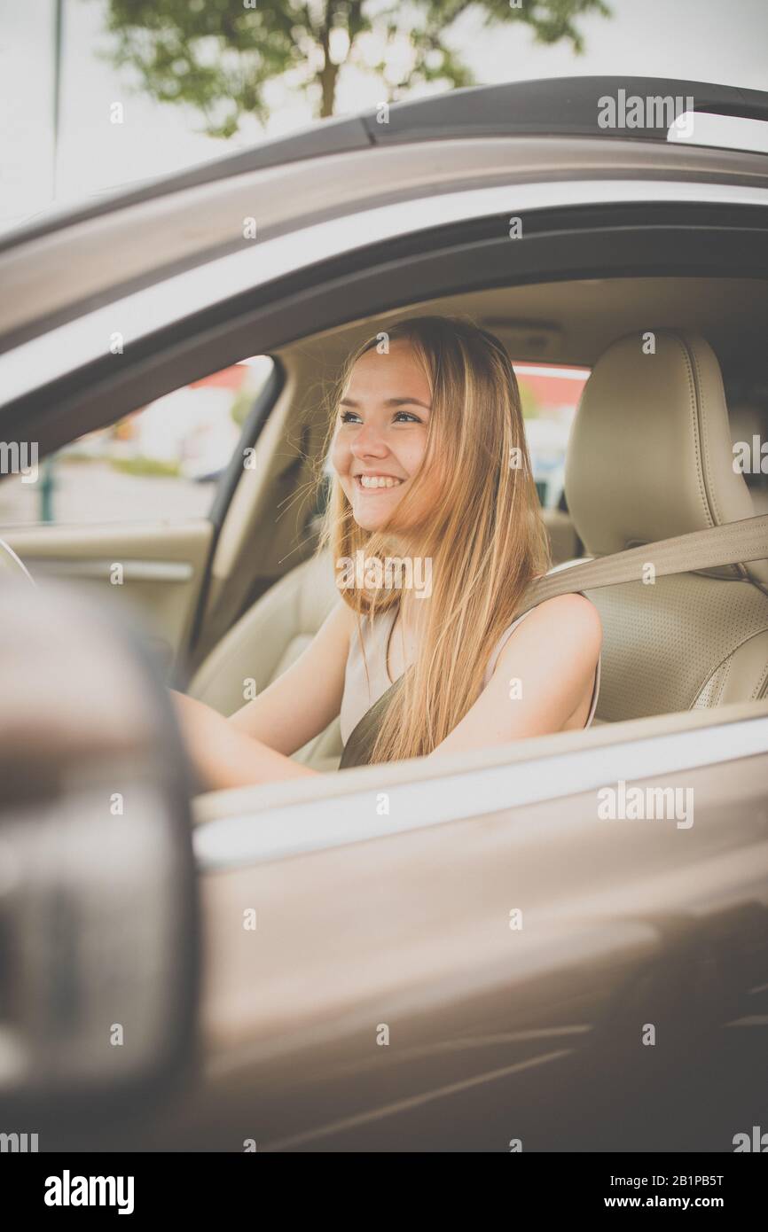 Cute female teen driver enjoying her freshly acquired driving license ...