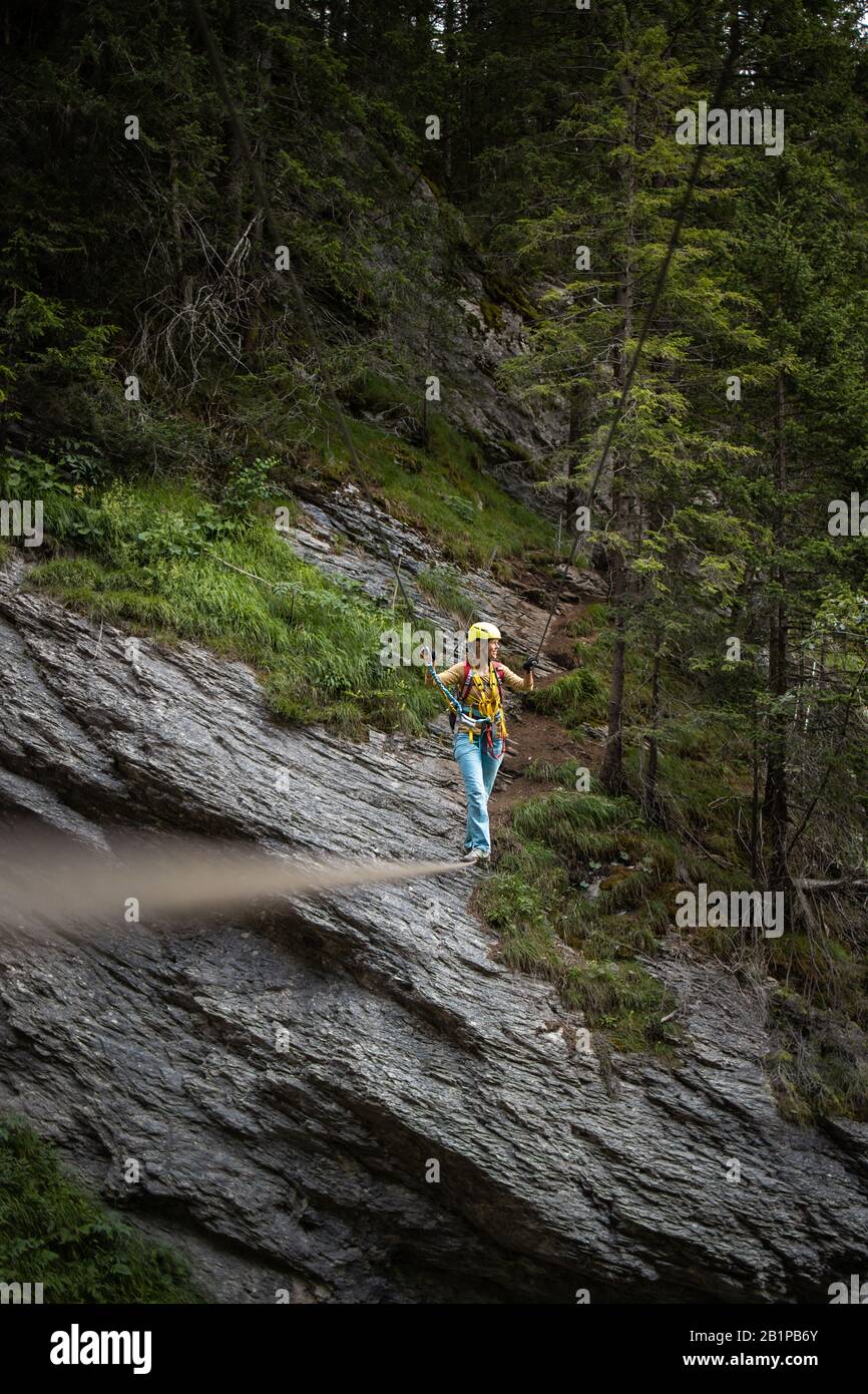 Pretty, female climber on a via ferrata - climbing on a rock in Swiss ...