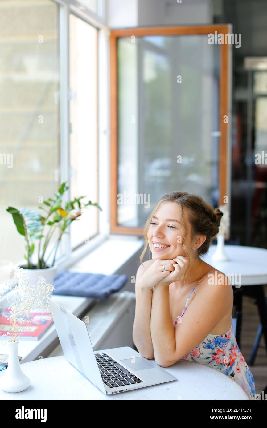Female caucasian student sitting at cafe and surfing internet by laptop ...