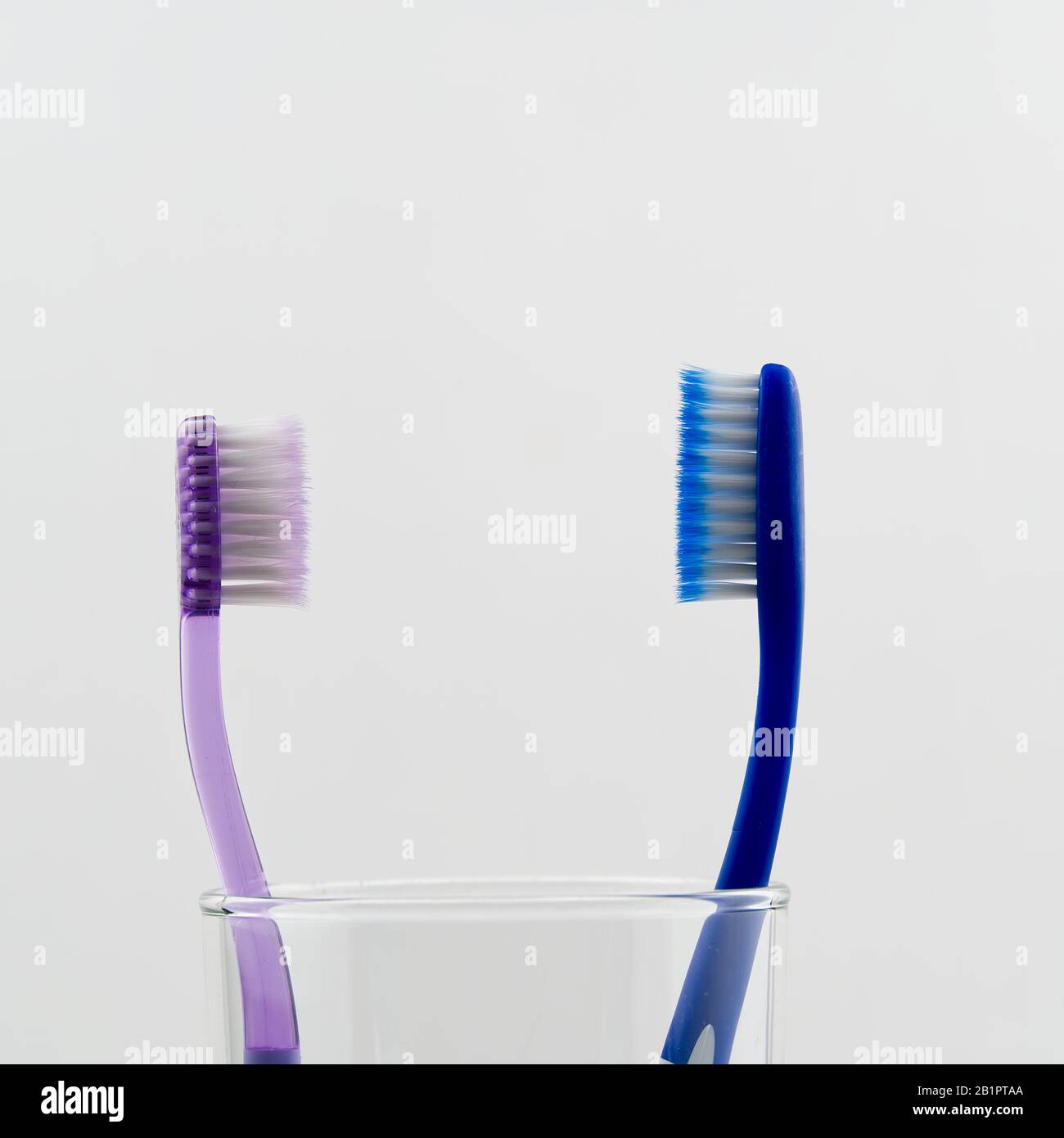 Pair of pink and blue toothbrushes in glass at bathroom isolated over ...