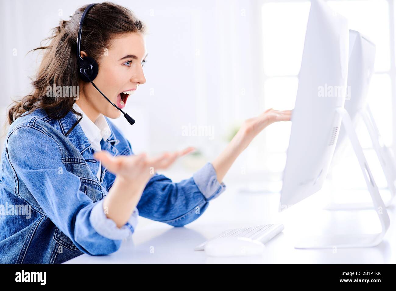 Surprised female customer support operator in the office with headset ...