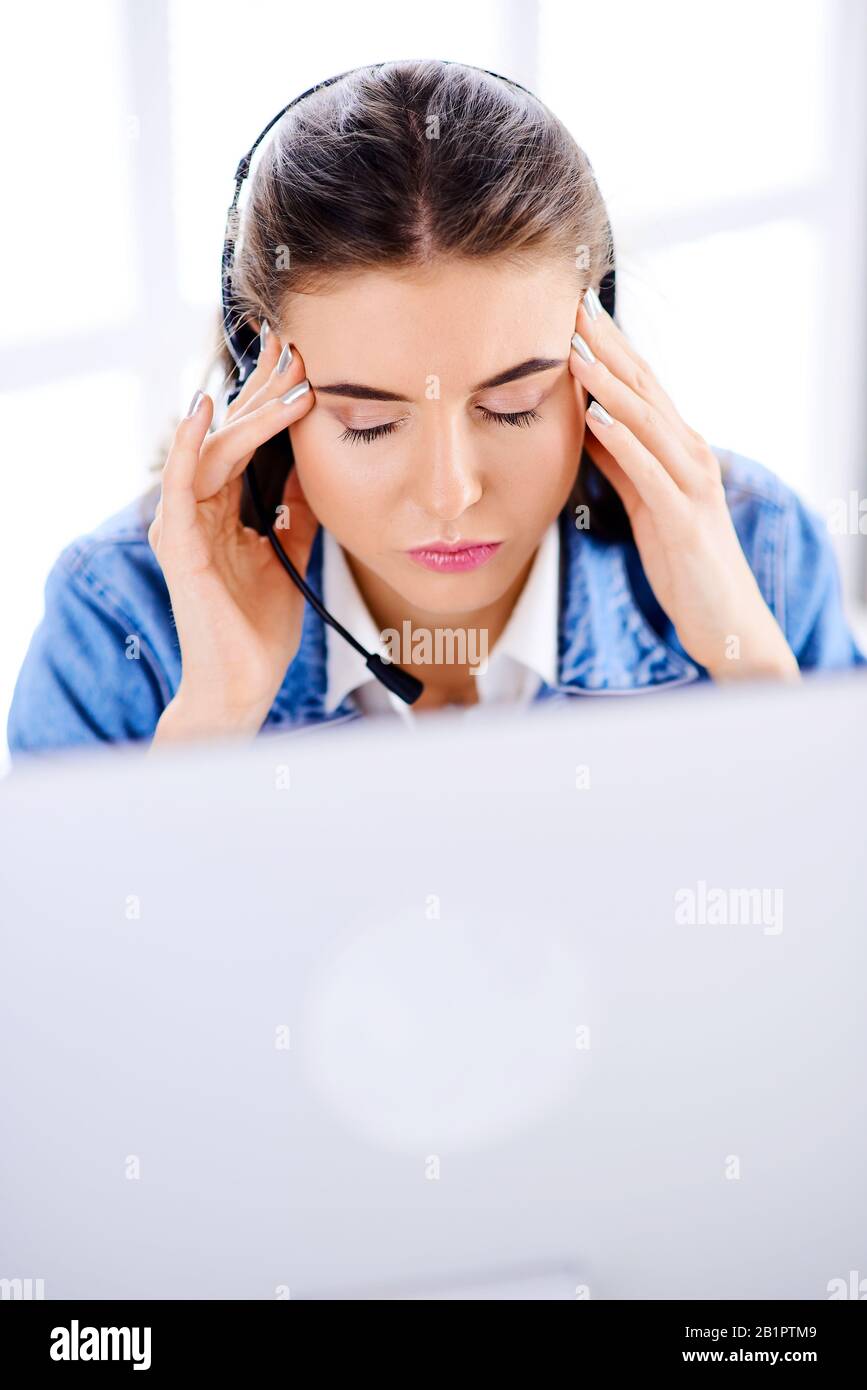 Tired female customer support operator in the office with headset Stock ...