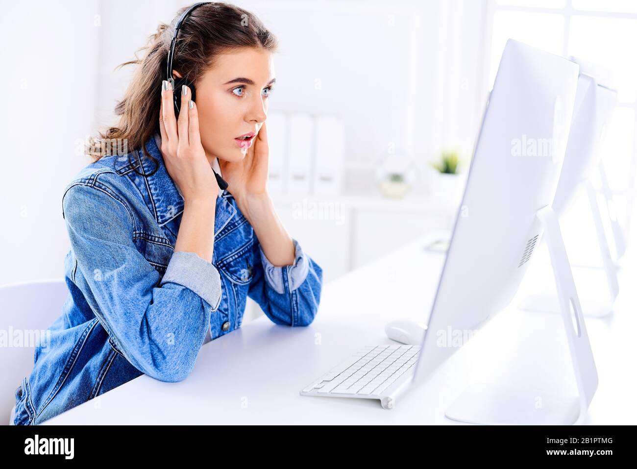 Surprised female customer support operator in the office with headset ...