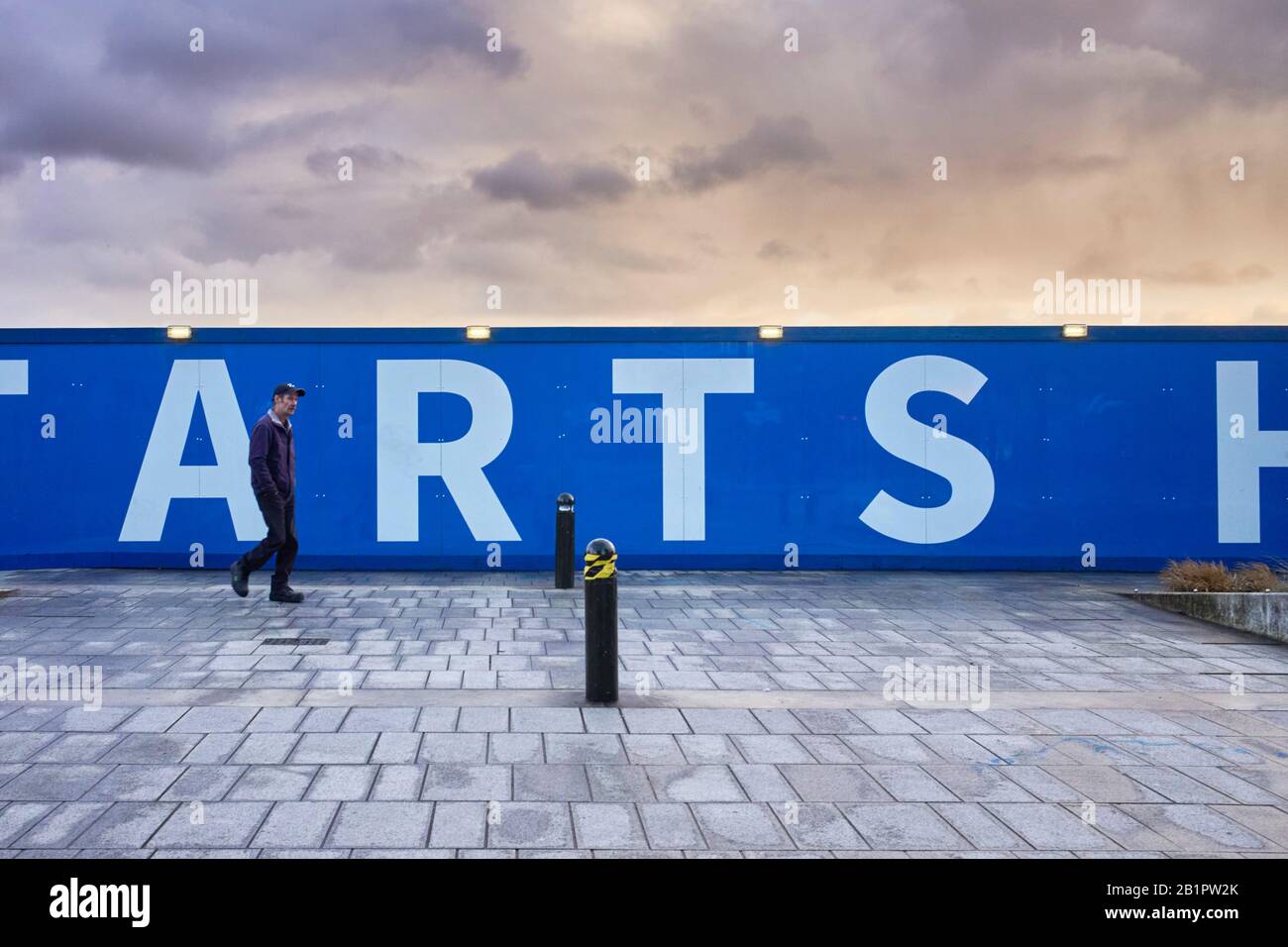 Street hoarding with the word Art in big letters and a man walking past ...