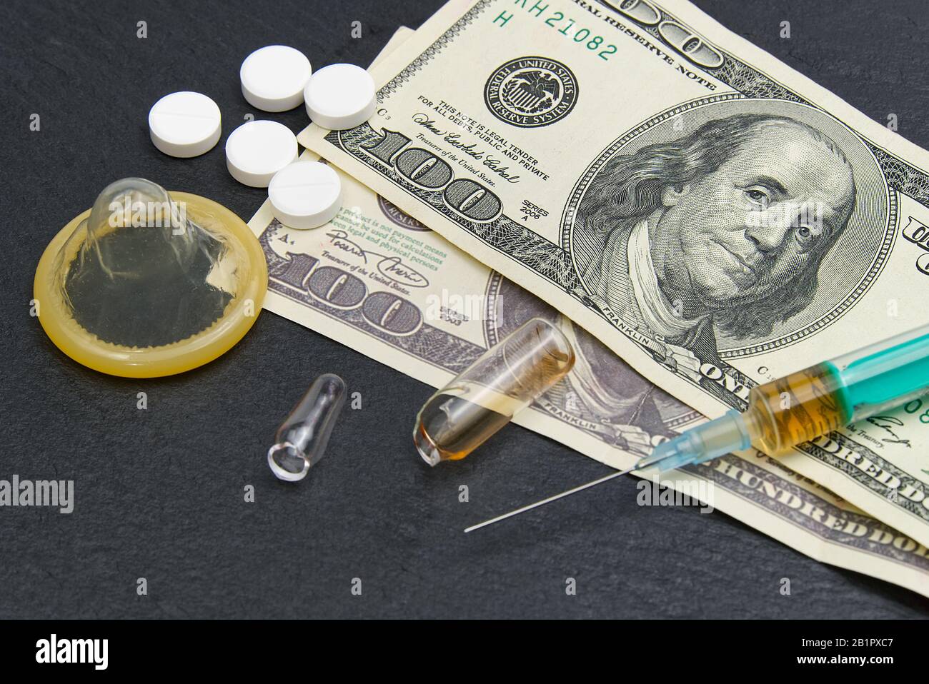 Money and pills with drugs and a syringe on black Stock Photo - Alamy