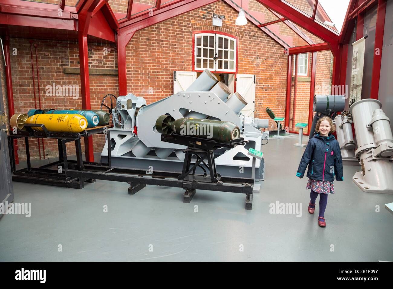 Young child tourist girl kid visitor walking past a Squid mortar system ...