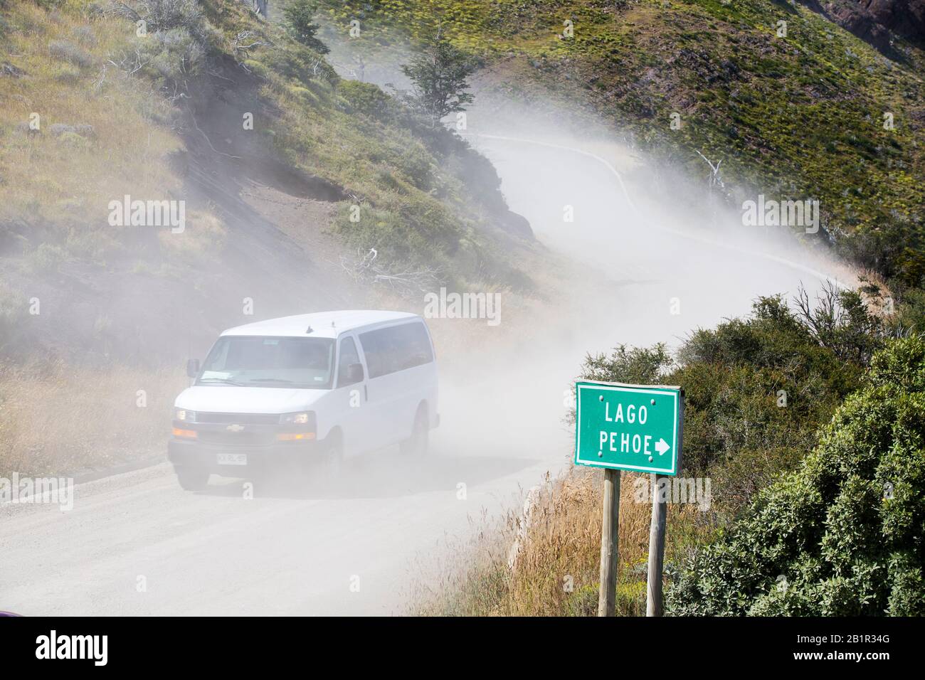 Vehicles kicking up dust on a gravel track in Torres del Paine national ...