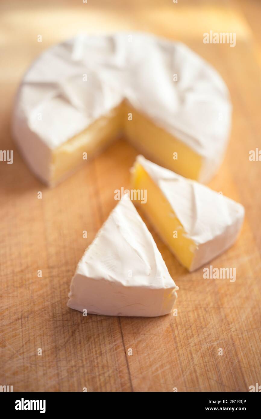 Camembert cheese with two triangles slices on a wooden board Stock ...