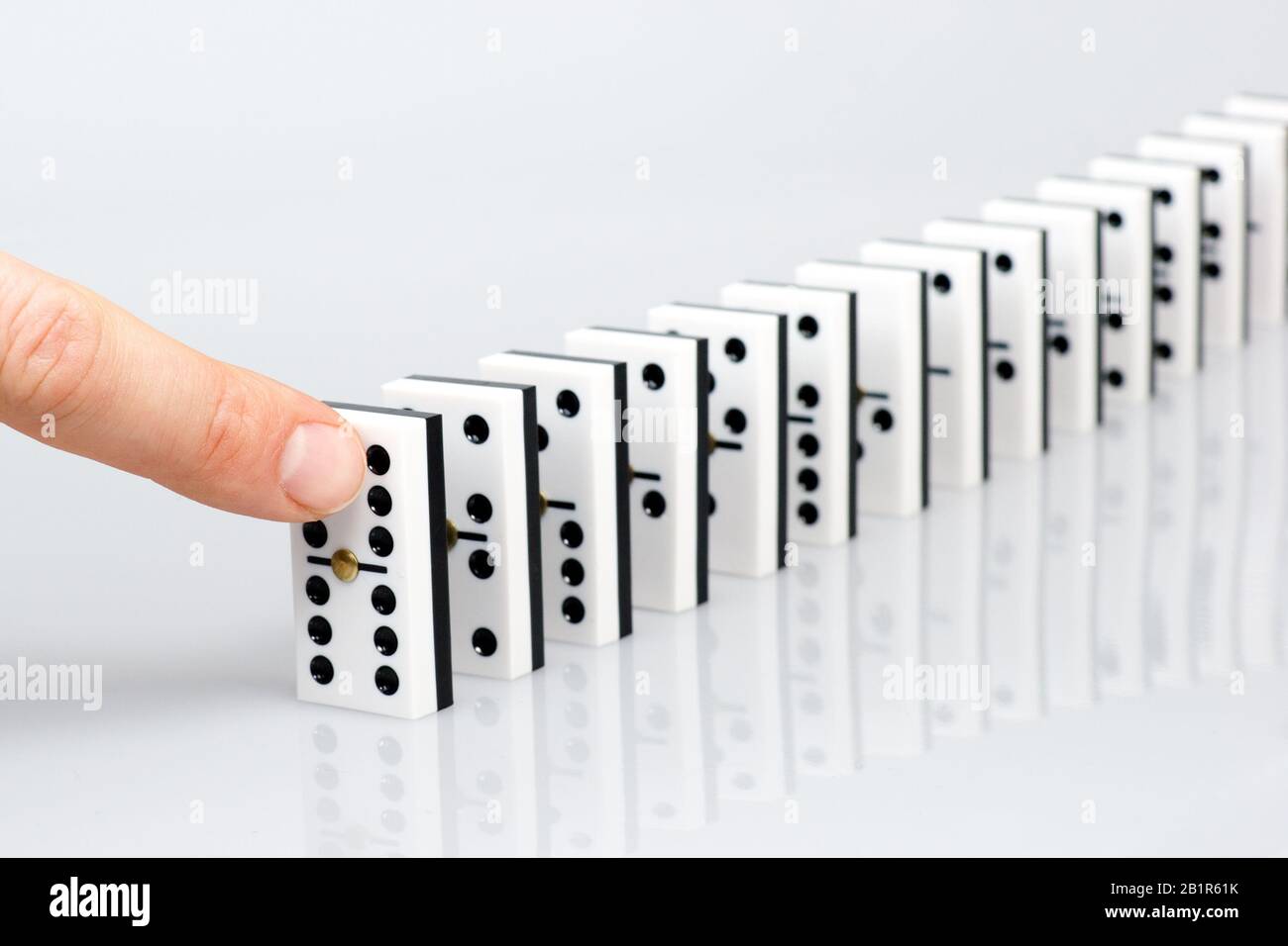 Finger ready to start domino chain reaction Stock Photo - Alamy