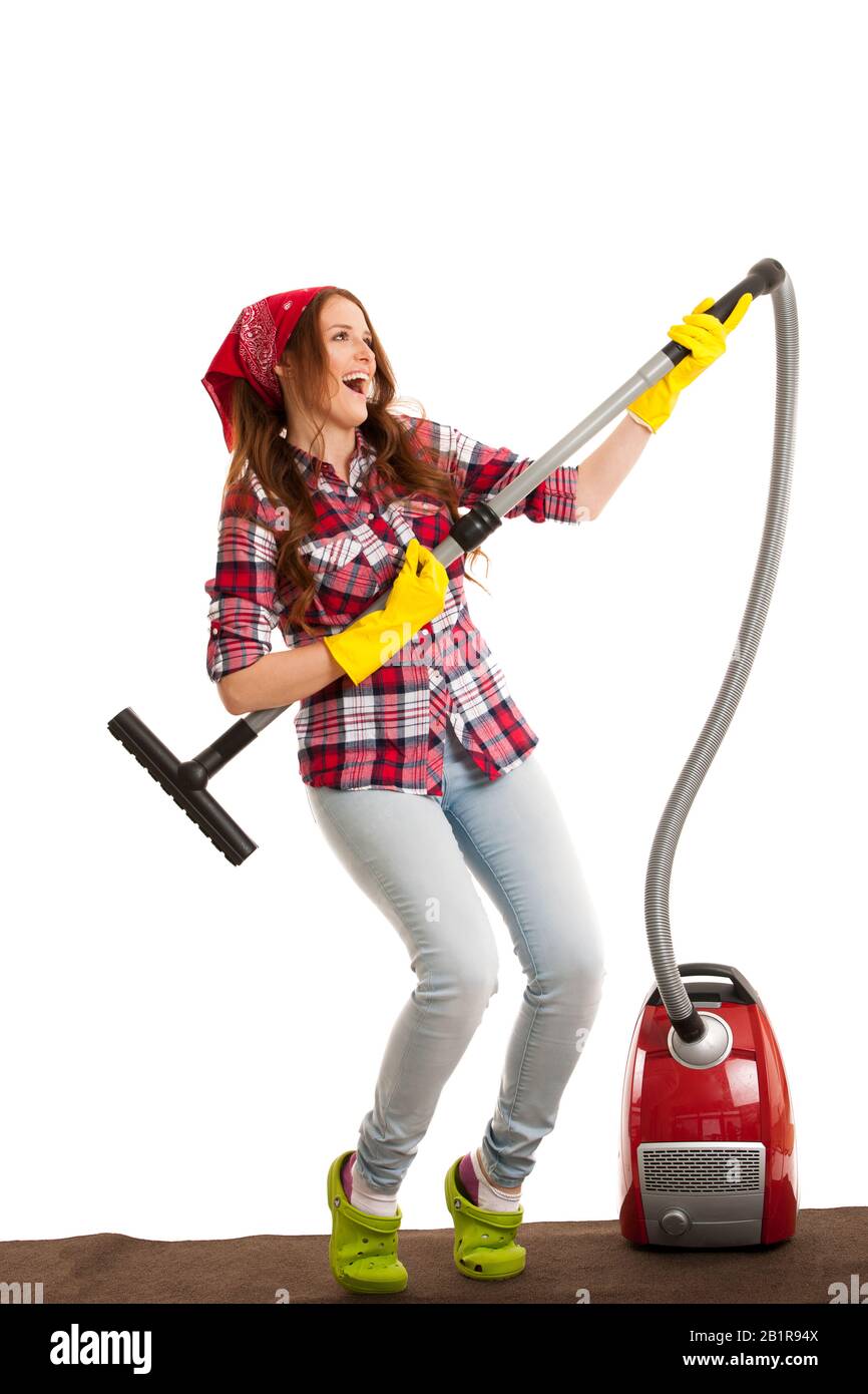 Happy young woman singing as she is cleaning with vacuum cleaner ...