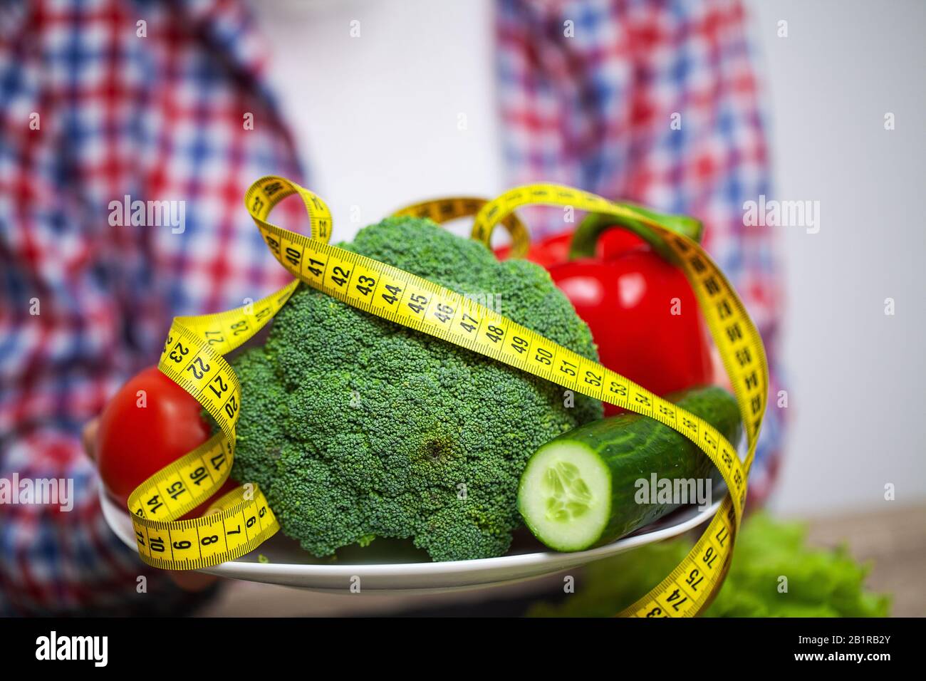 Woman holds vegetables in her hands with a measuring tape Stock Photo ...