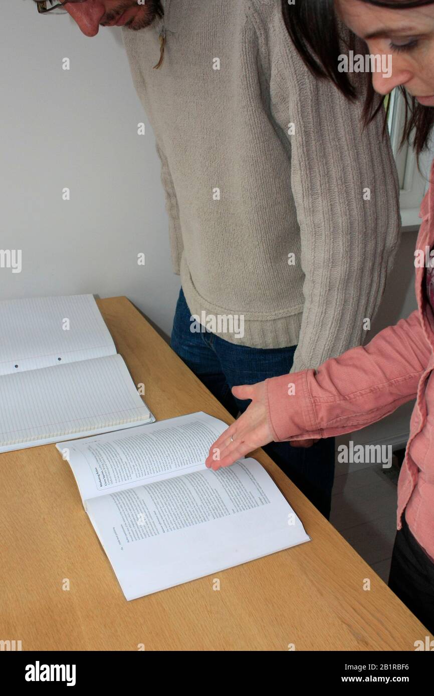 Couple at home reading a page in a book Stock Photo - Alamy