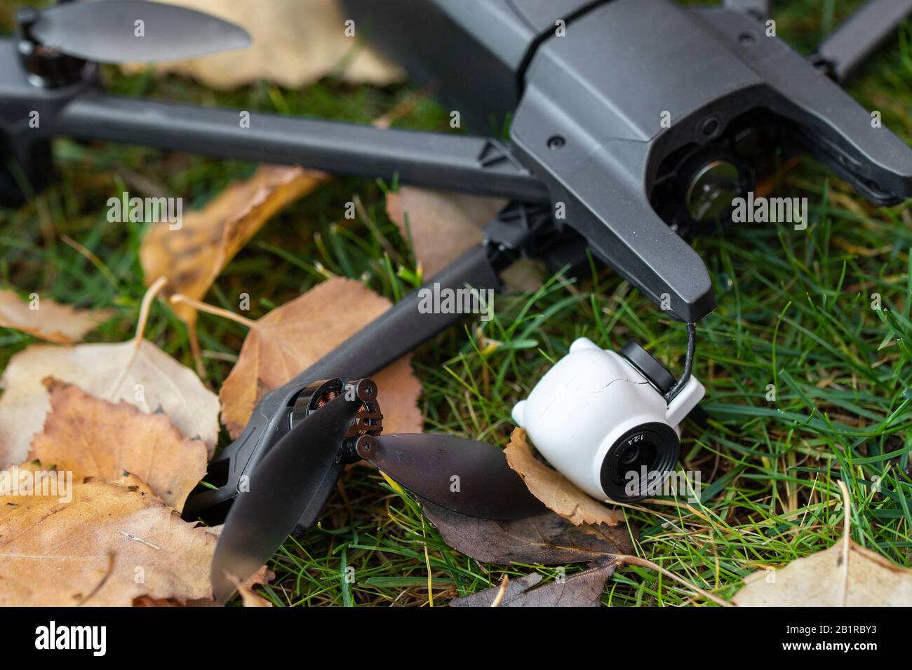 Broken black quadcopter drone uav lying on green grass lawn on ground ...