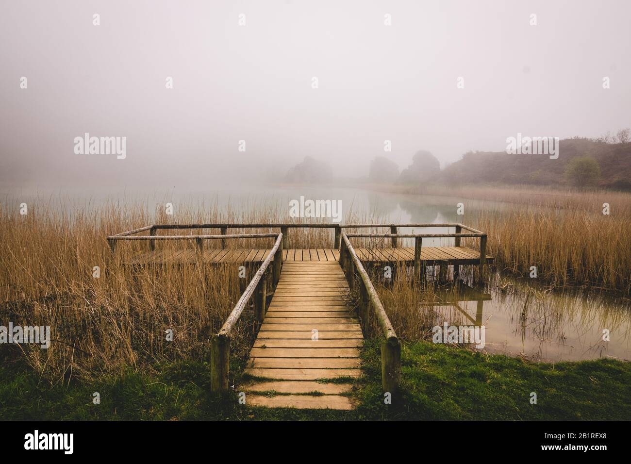 Foogy scene with a lake and a wood structure Stock Photo - Alamy