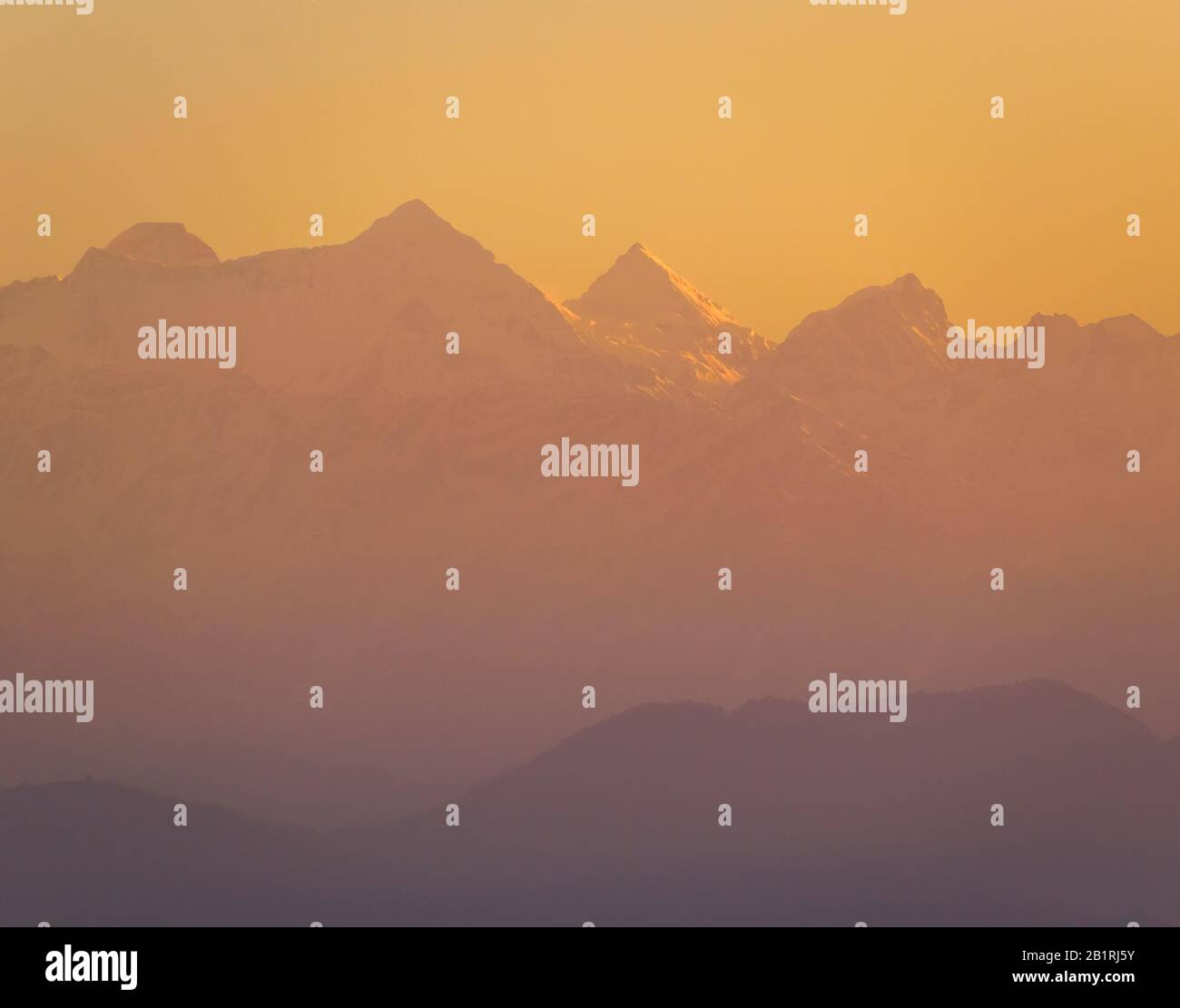 The yellow-orange morning light hits the scenic Himalayan peaks in the ...