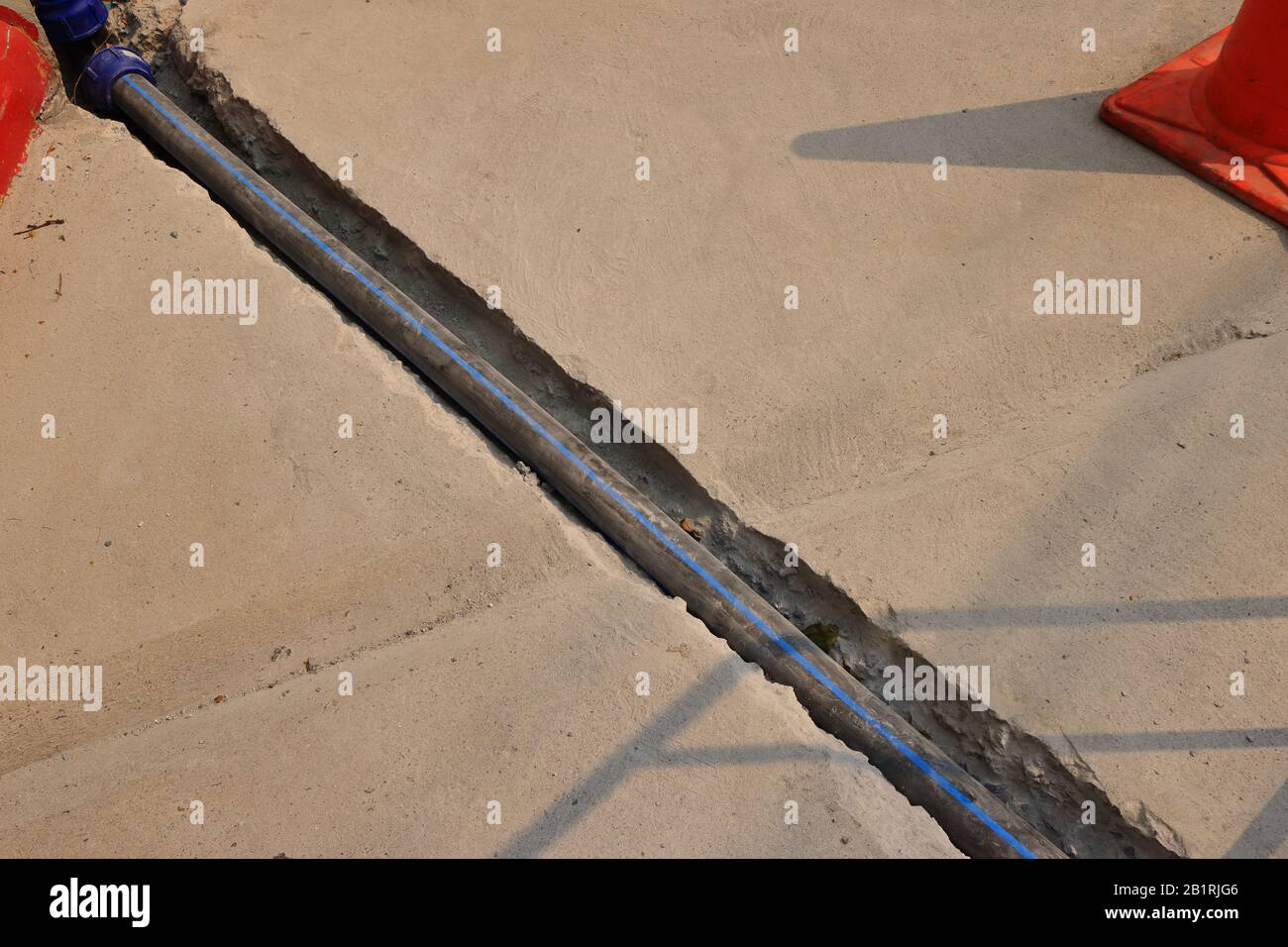 Process of burying water pipe underground by laying it in a trench dug ...