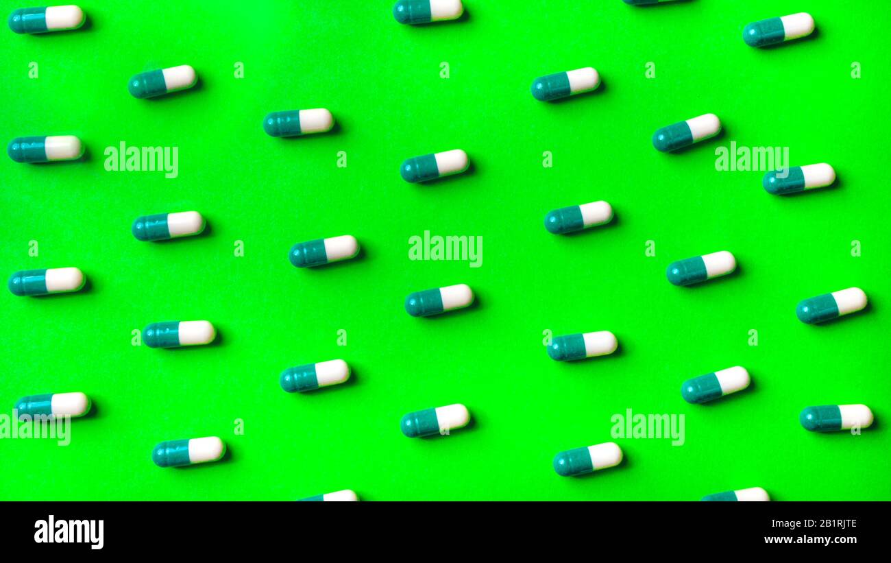 Pattern of white and green pills on a green background. Heap of ...