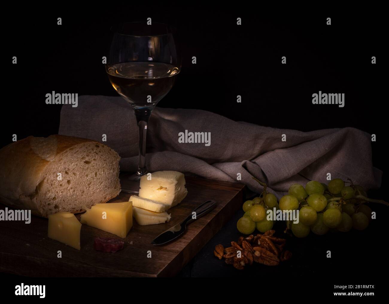 Brie and swiss cheese onwooden cheese board, accompanied by fruit, nuts ...