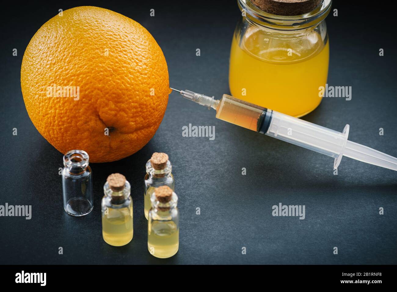 Orange with syringe injection colored liquid Stock Photo - Alamy