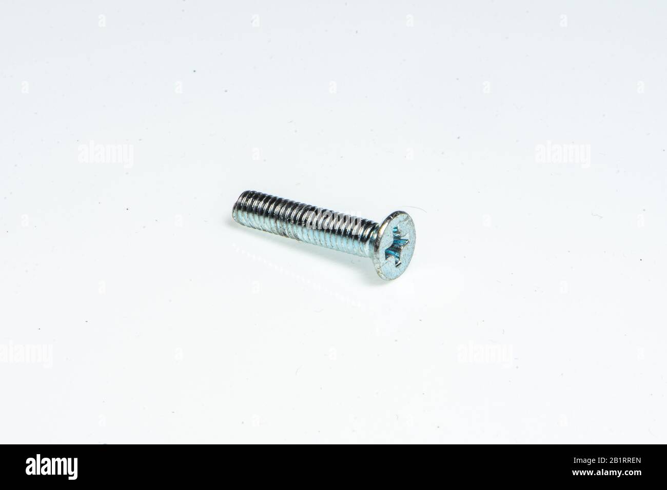 Detail of a small steel screw on a white background Stock Photo - Alamy