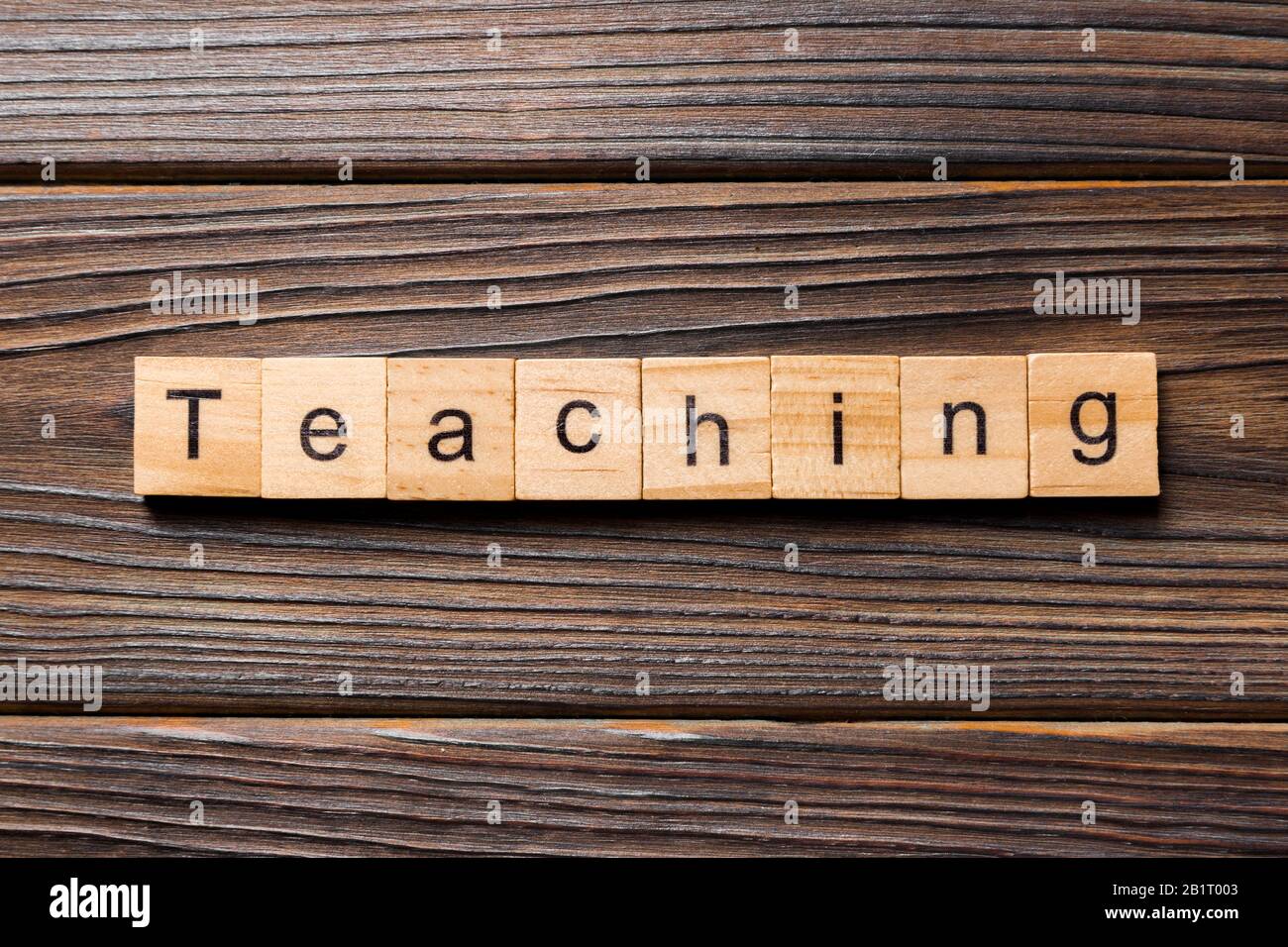TEACHING word written on wood block. TEACHING text on wooden table for ...