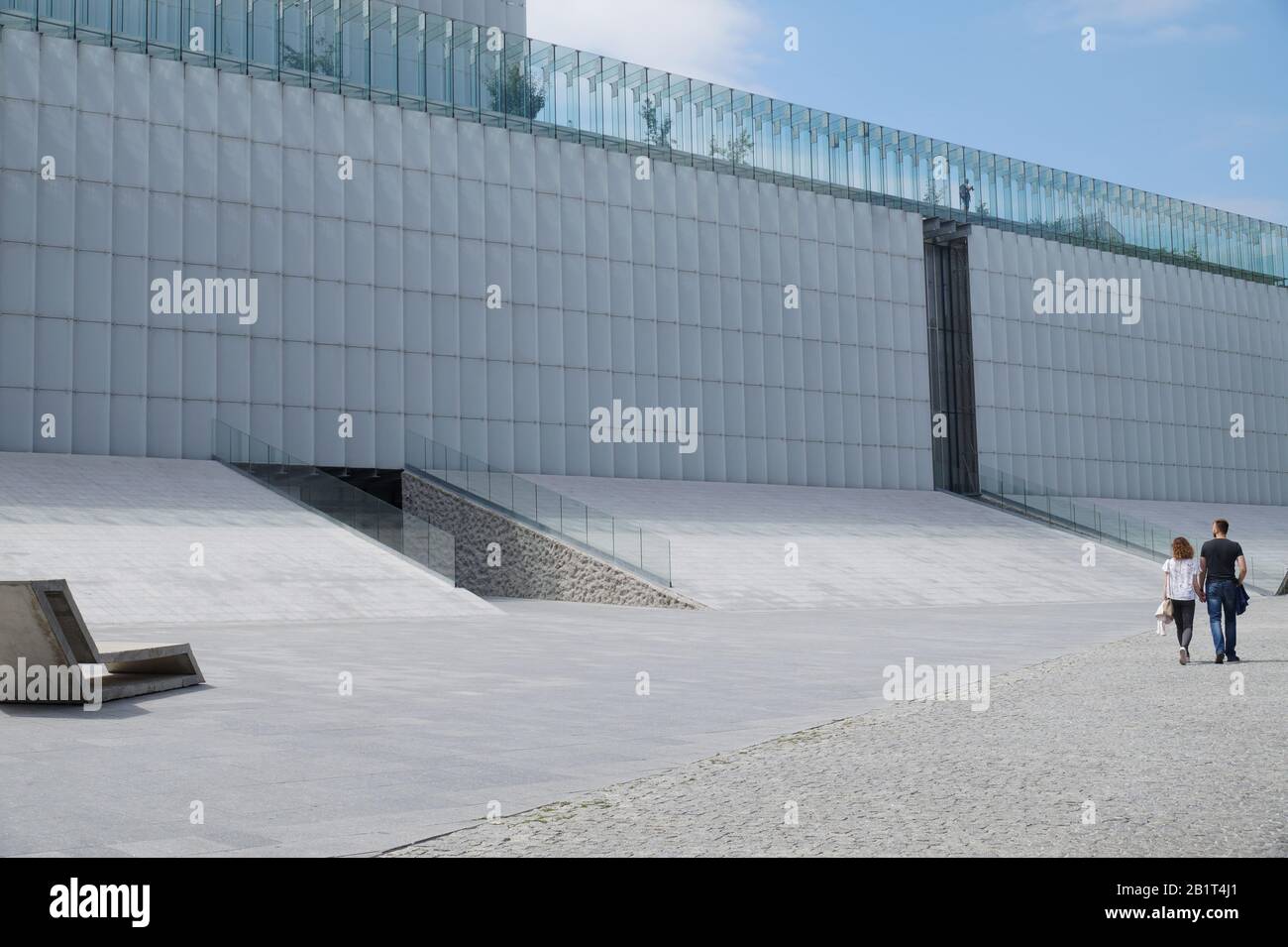 The girl and boy are walking along the modern building watching him ...
