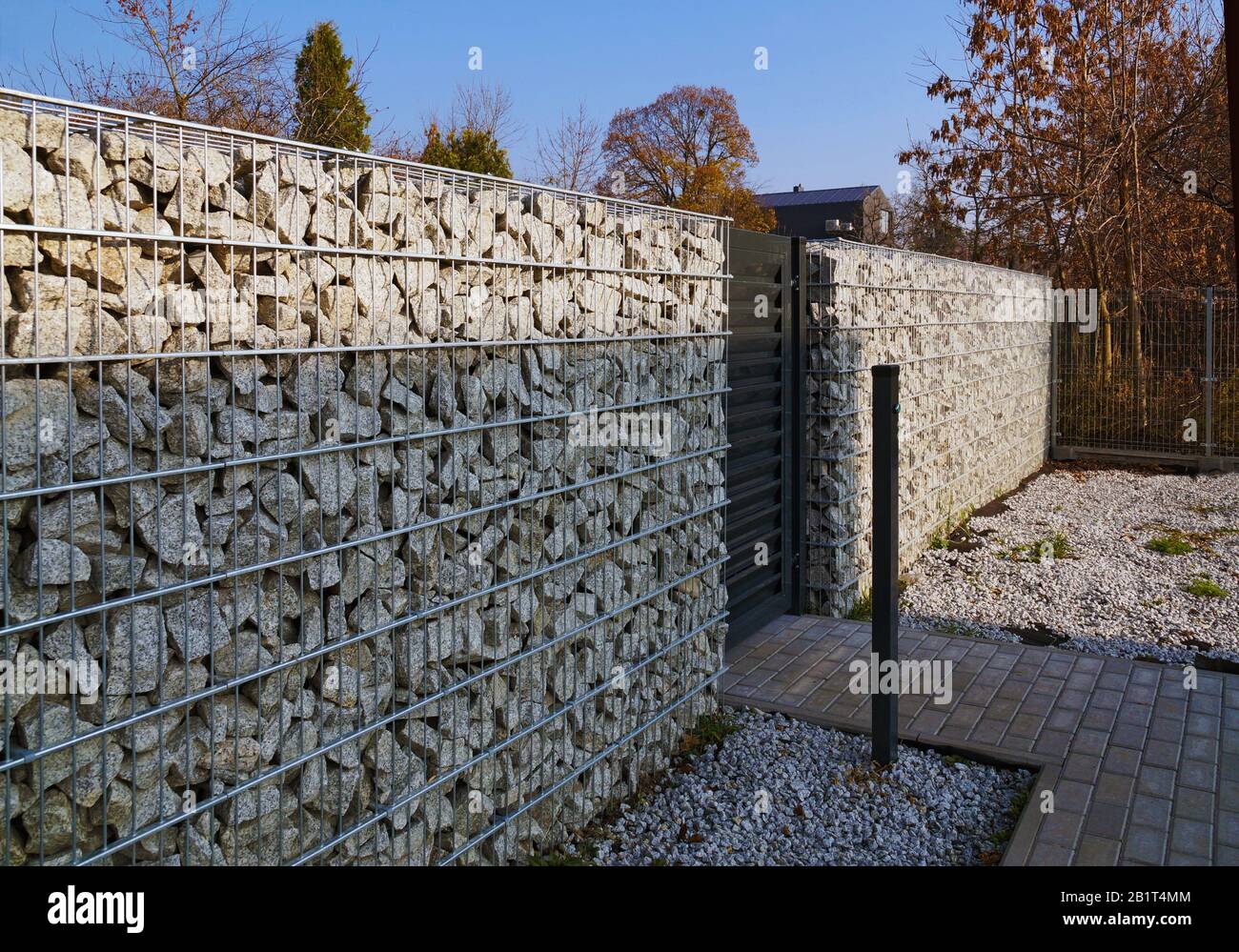 Fence made of gabions. In the wall, the gate, before the gate, a post ...