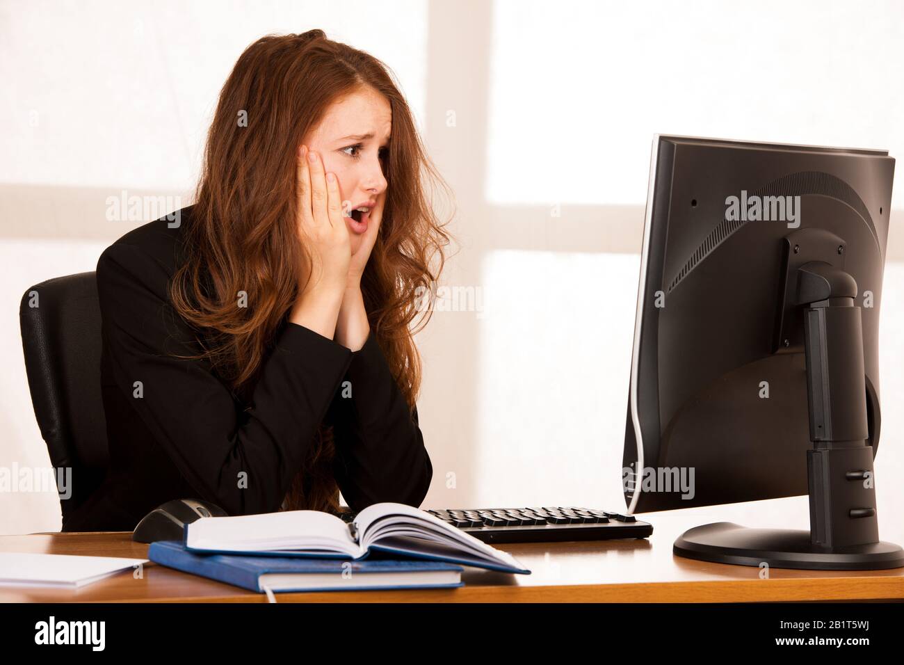 Frightened stressed woman working at her desk in the office, reading ...