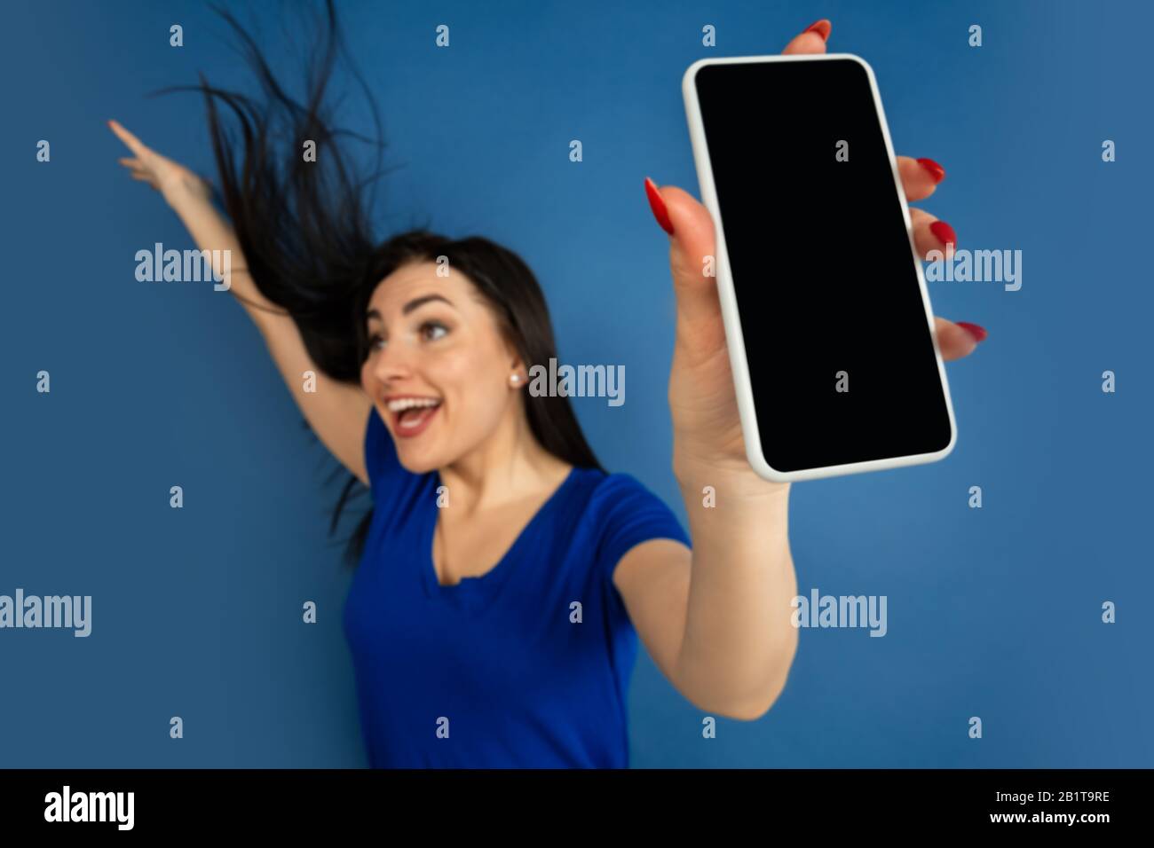 Showing phone screen. Beautiful caucasian woman's portrait on blue ...