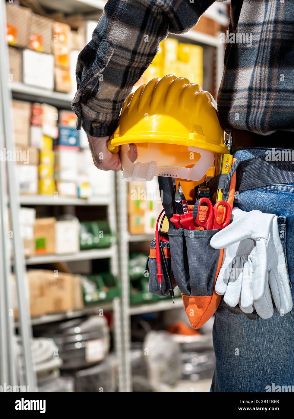 Electrician in the electrical component store holds the helmet and ...