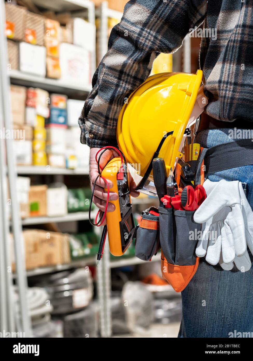 Electrician holds multimeter tester in hand, helmet with protective ...