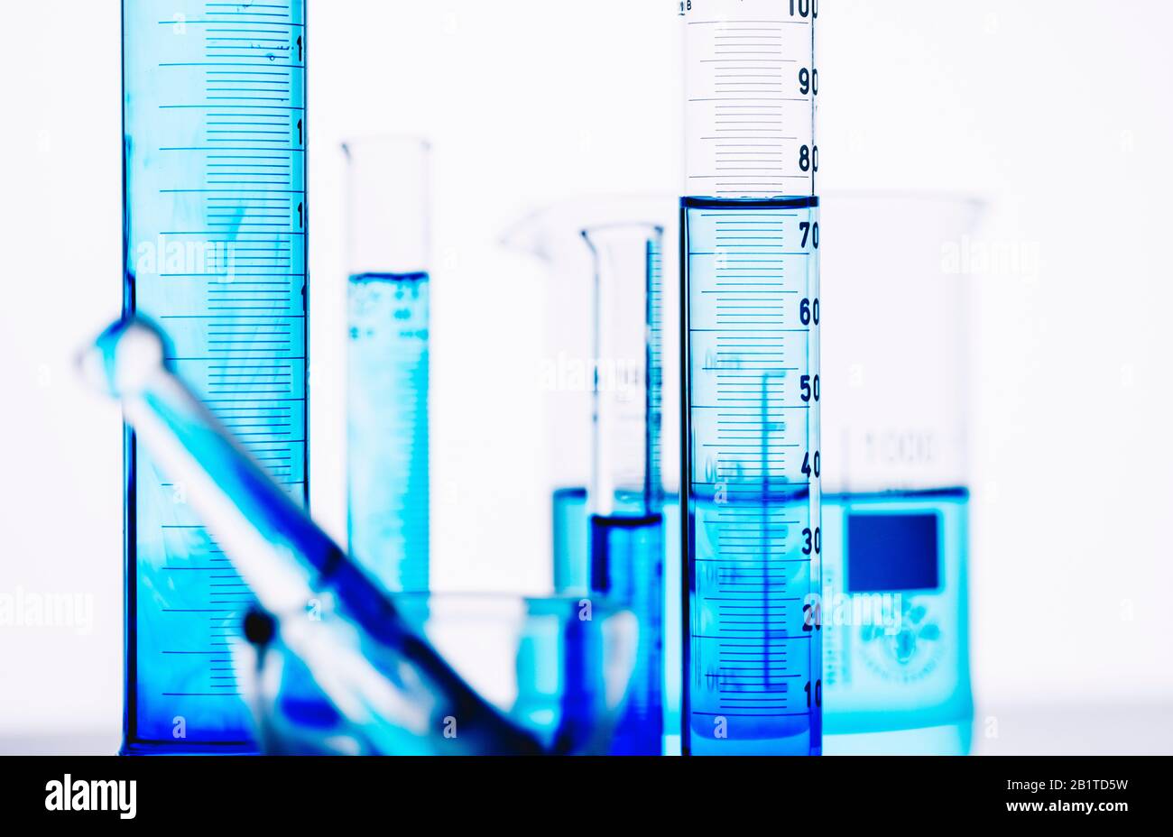 Laboratory test equipment with blue liquid inside on white background ...
