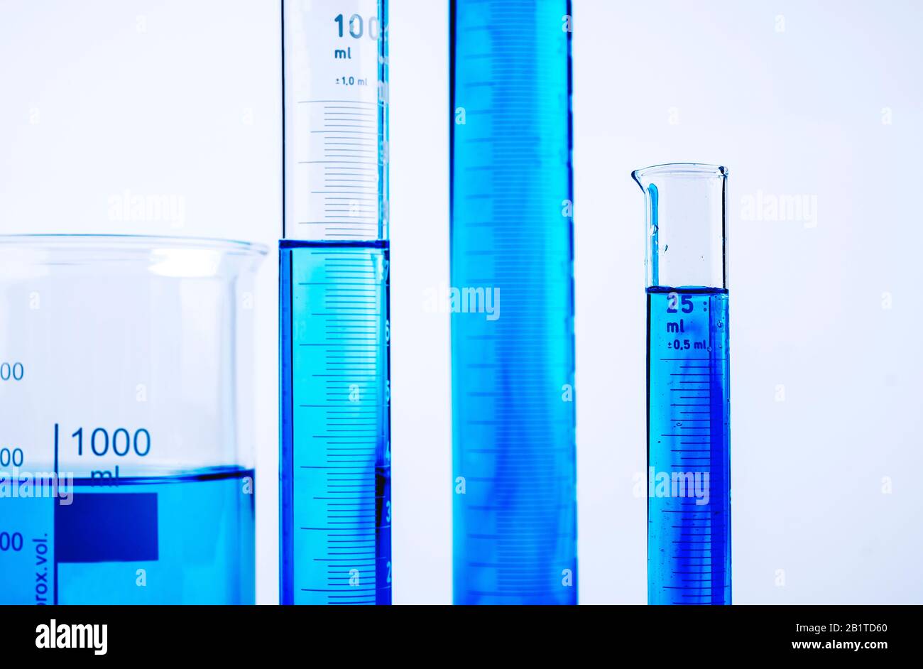 Laboratory test equipment with blue liquid inside on white background ...