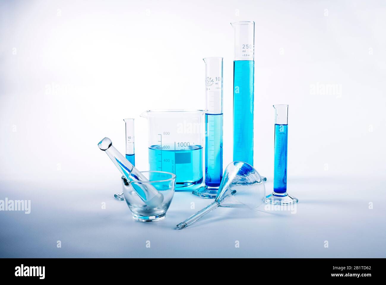 Laboratory test equipment with blue liquid inside on white background ...