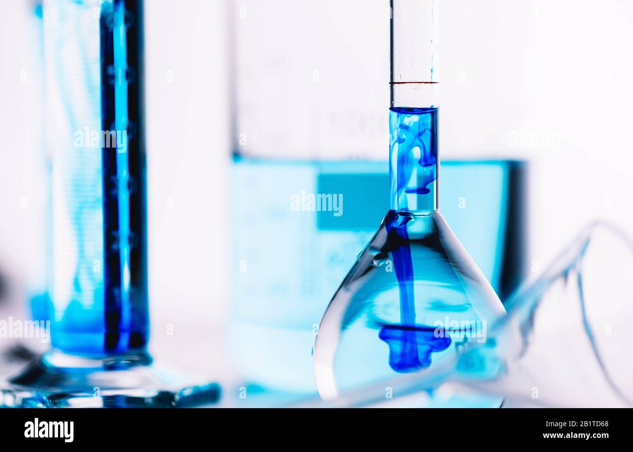 Laboratory test equipment with blue liquid inside on white background ...