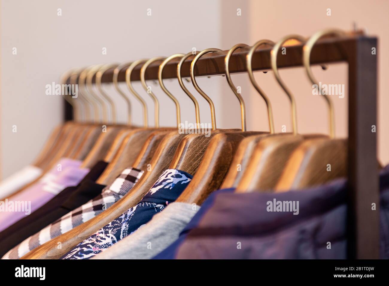 Closeup colorful male, female clothes in boutique hanging on hangers ...