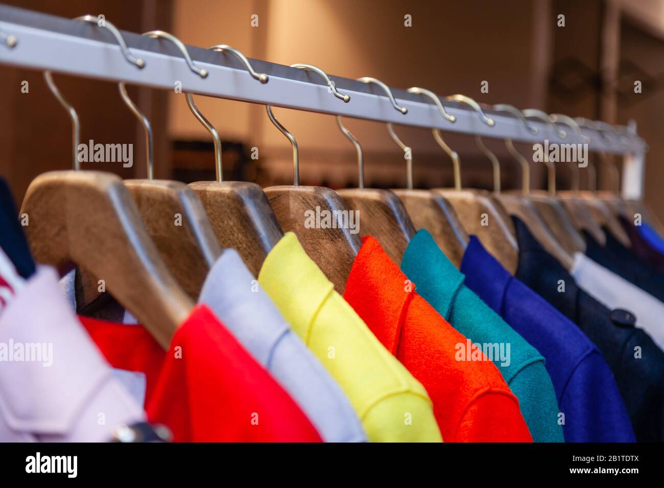 Closeup colorful male, female clothes in boutique hanging on hangers ...