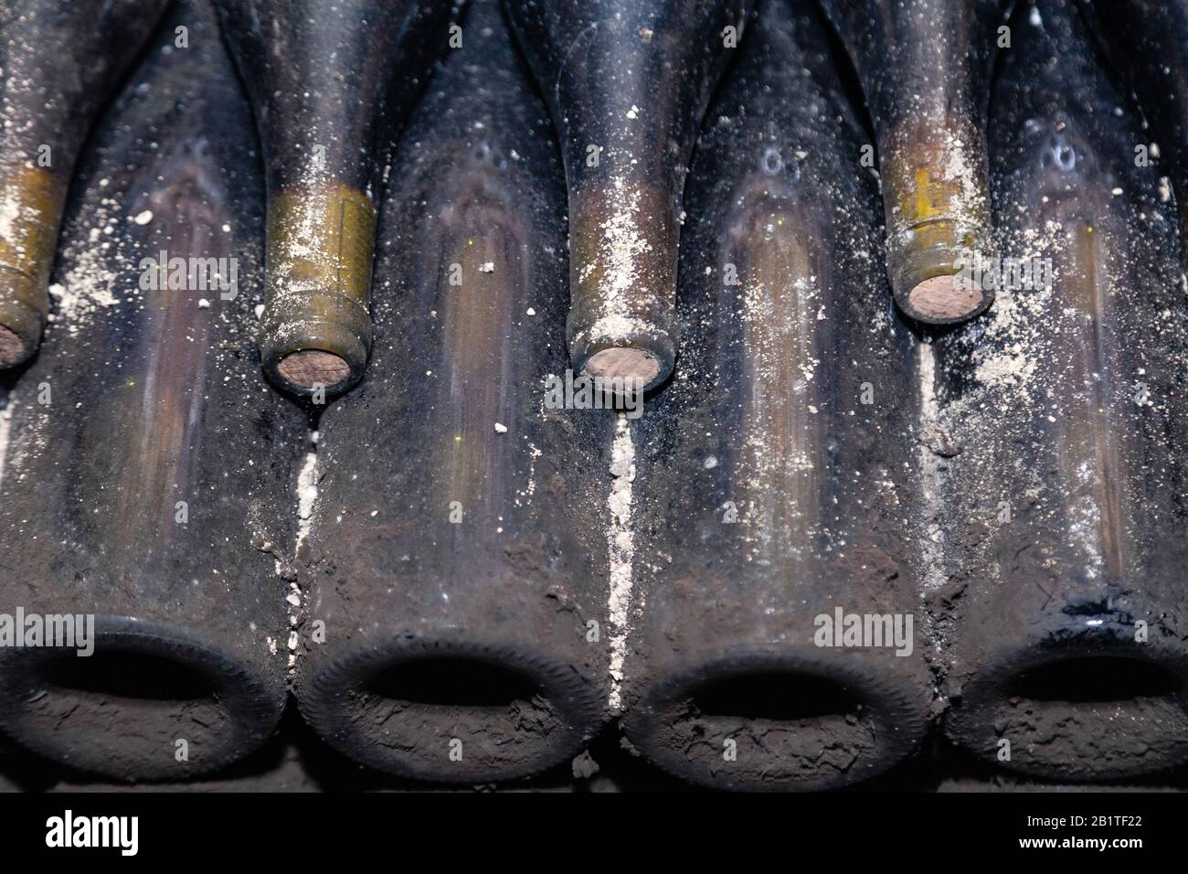 Ancient dark dusty wine bottles aging in underground cellar in rows ...