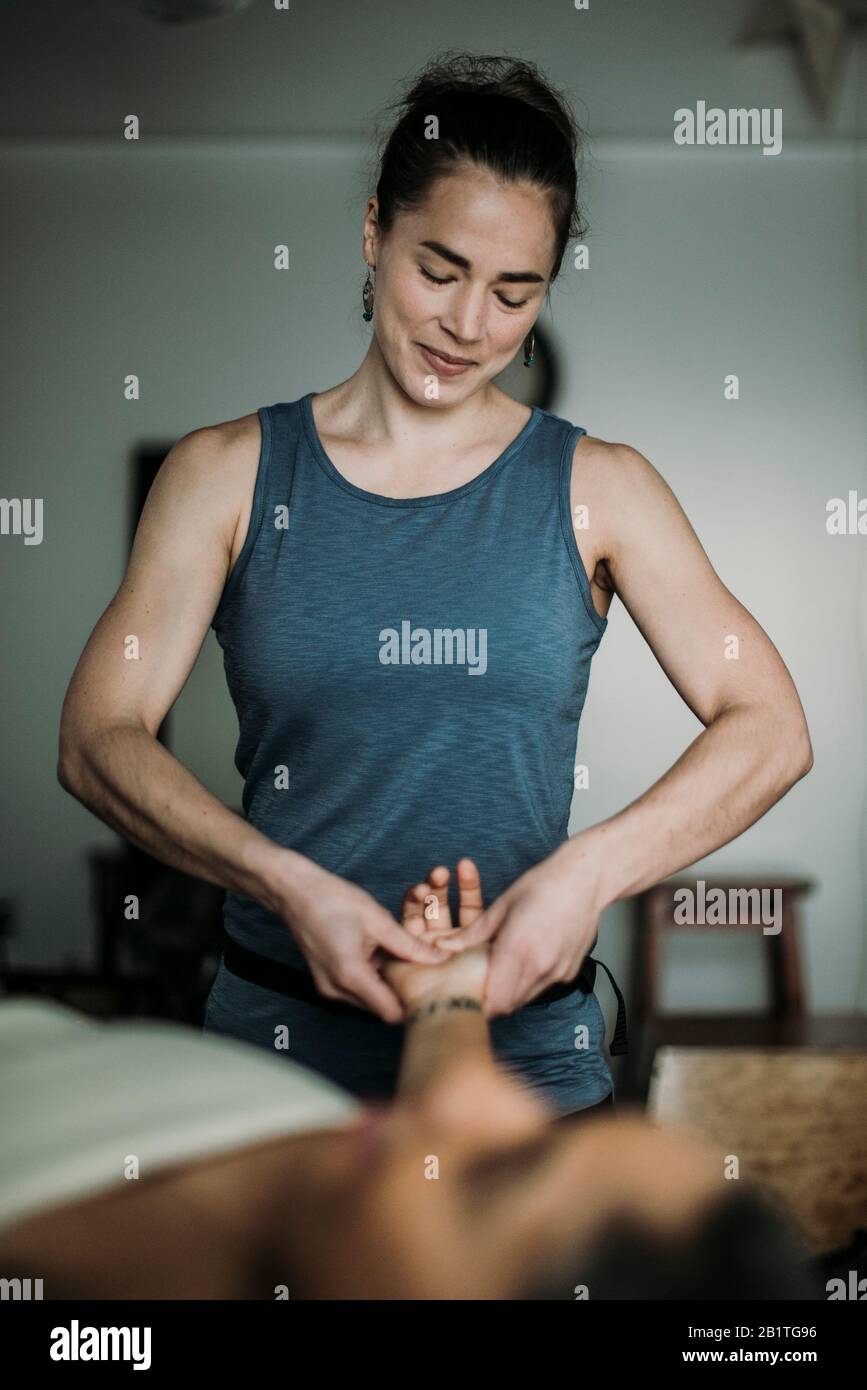 A fit female massage therapist smiles while treating a patient Stock ...