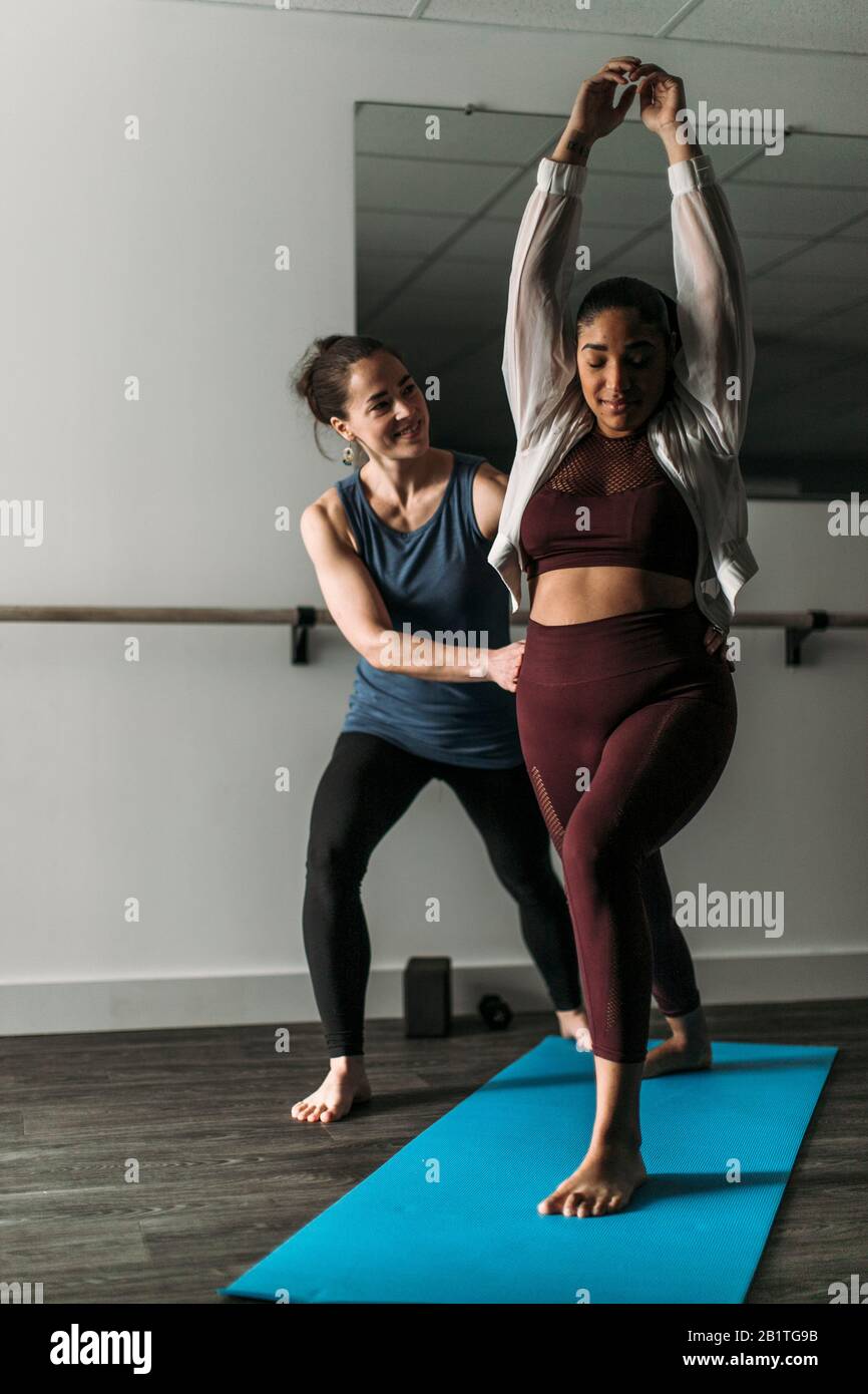 Two smiling friendly multi racial woman workout and train at a gym ...