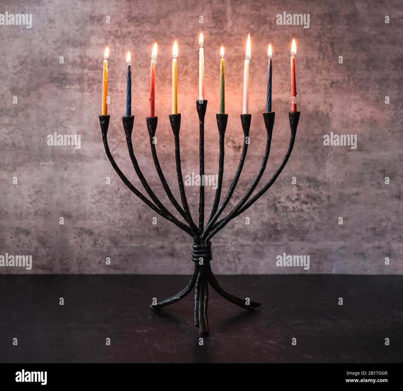 A menorah with candles lit for Hanukkah celebrations on a black table ...