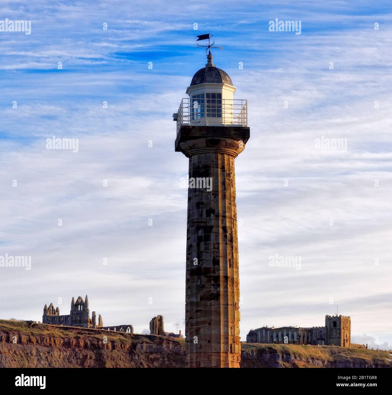 Whitby lighthouse with st marys church and the abbey ruins on the cliff ...