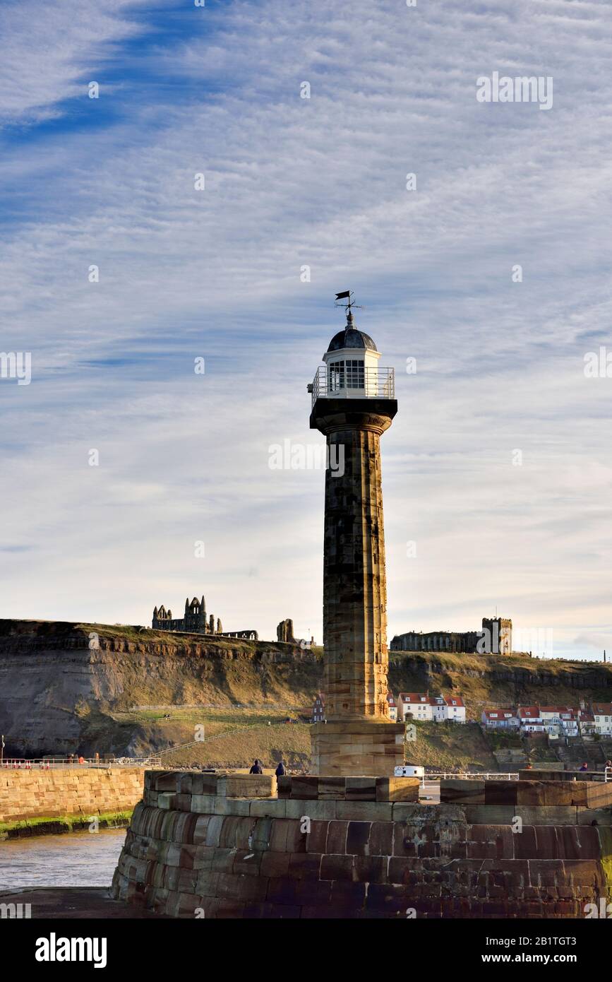 Whitby lighthouse with st marys church and the Abbey ruins on the cliff ...