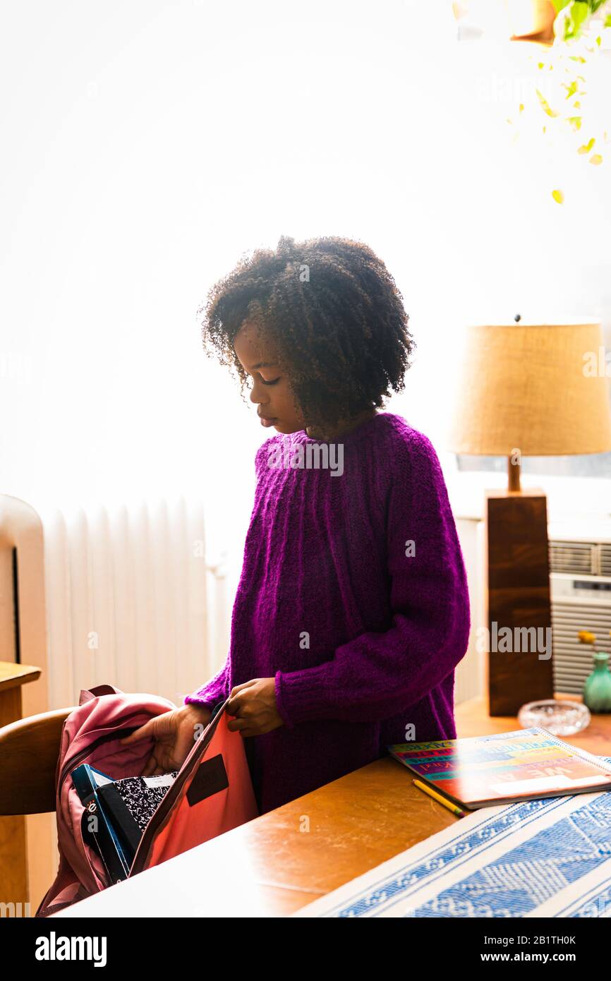 Girl packing books in backpack after finishing homework at home Stock ...