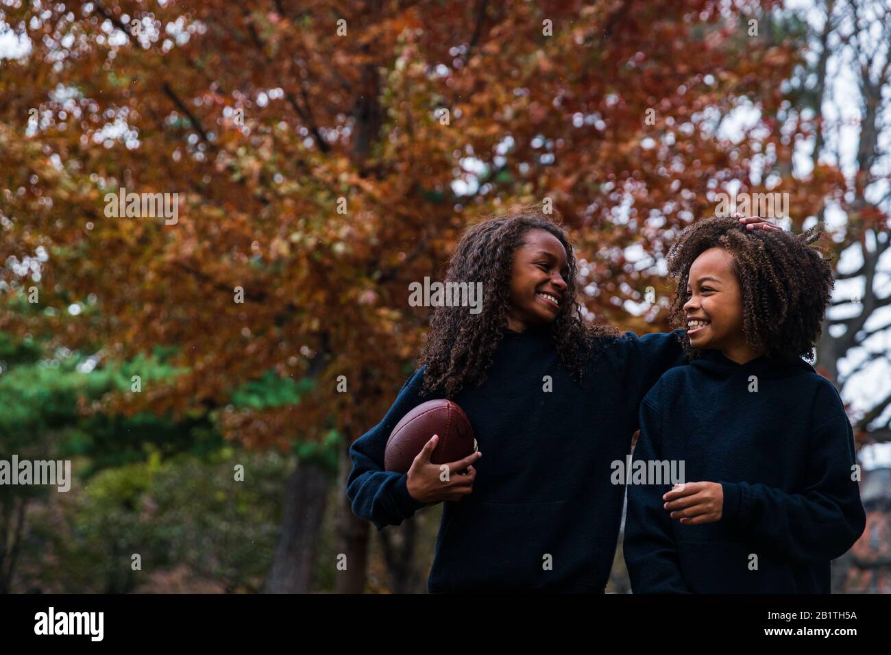 Smiling siblings with American football in park during autumn Stock ...